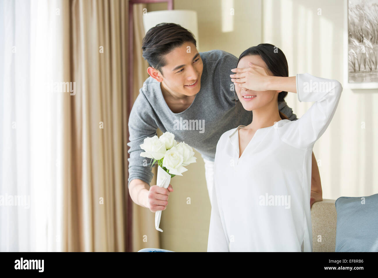 Young man surprising wife with flowers Stock Photo - Alamy