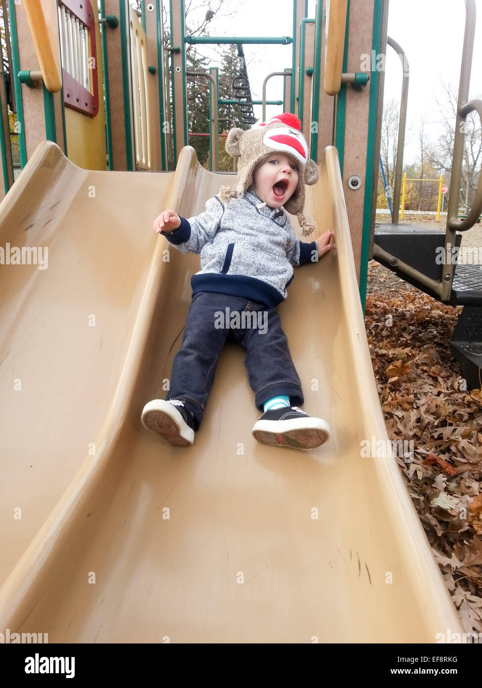 Boy sliding on playground Stock Photo - Alamy