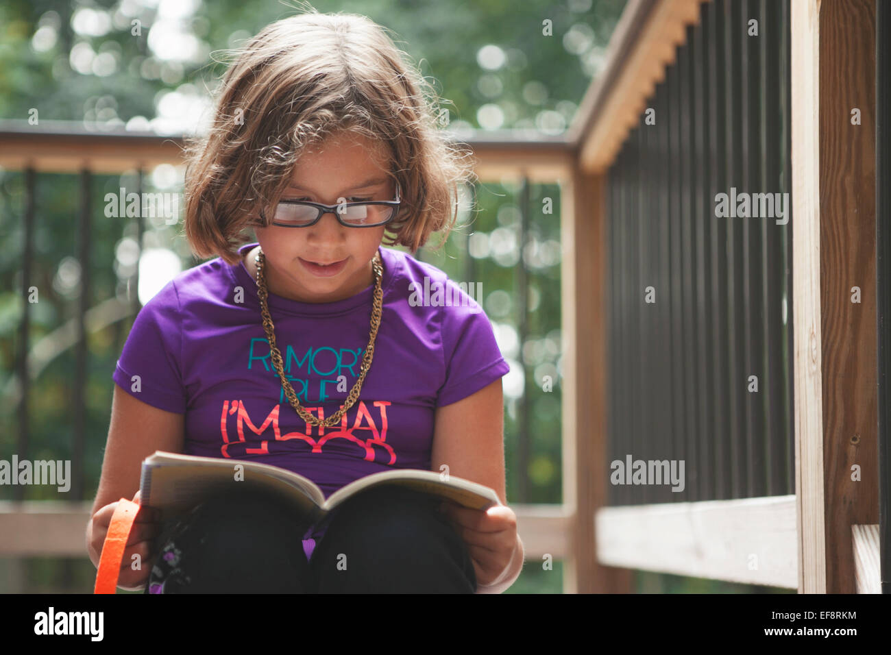 Girl (6-7) reading book on balcony Stock Photo - Alamy