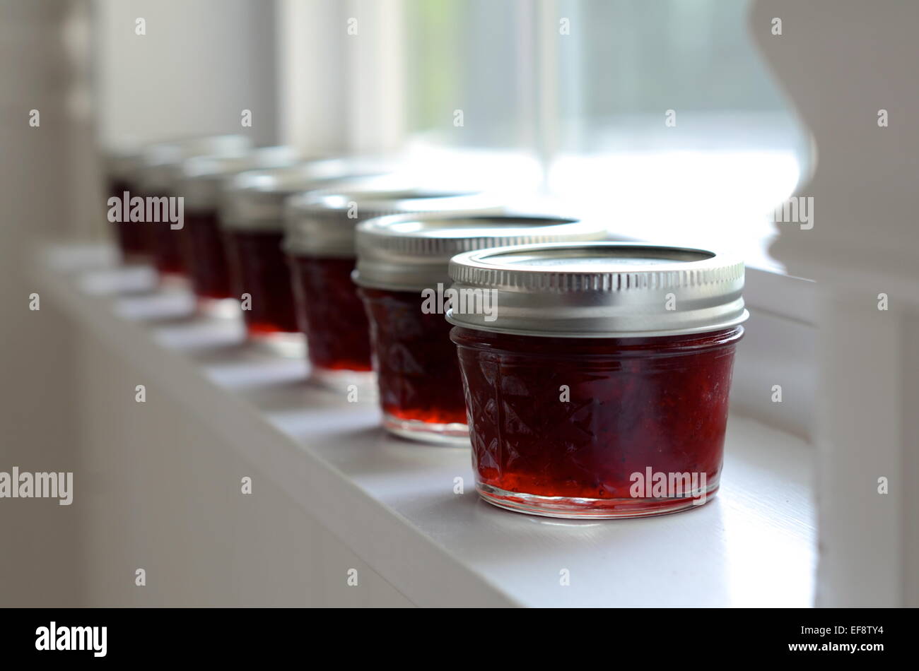 Row of red jam jars on window still Stock Photo - Alamy