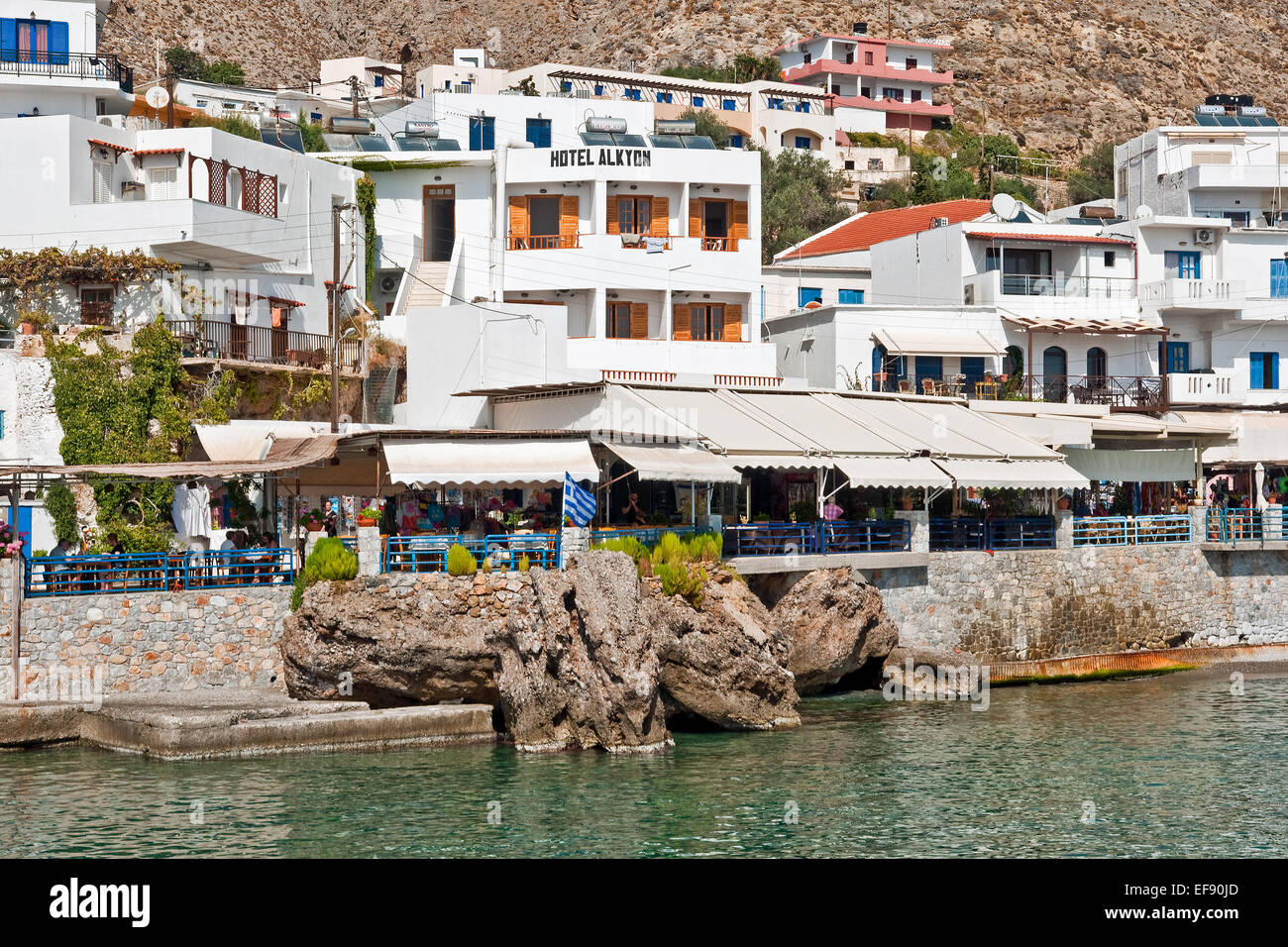 Waterfront restaurants line the tiny harbour of Sfakia, beach and ...