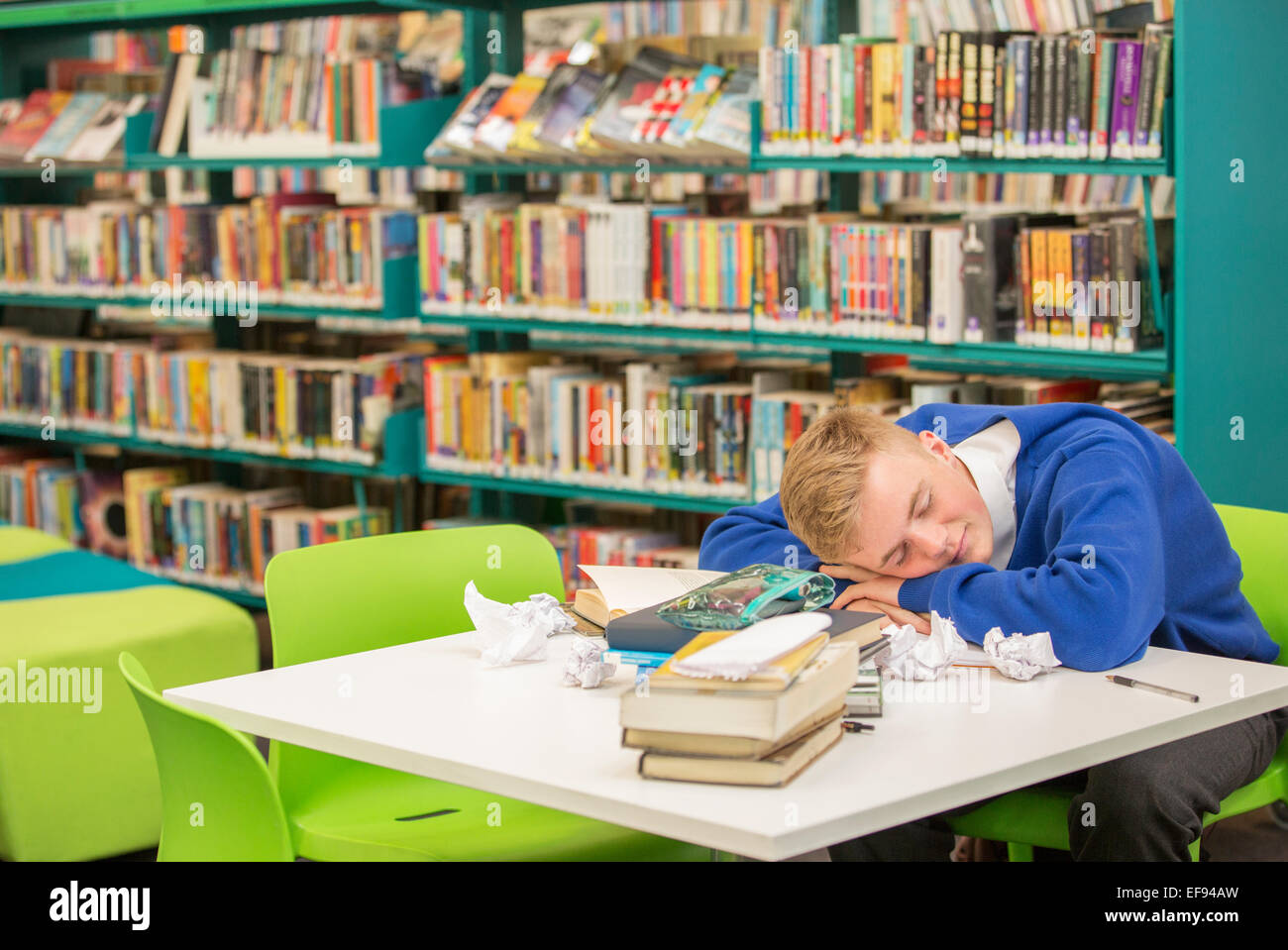 Exhausted student sleeping on table in library Stock Photo - Alamy