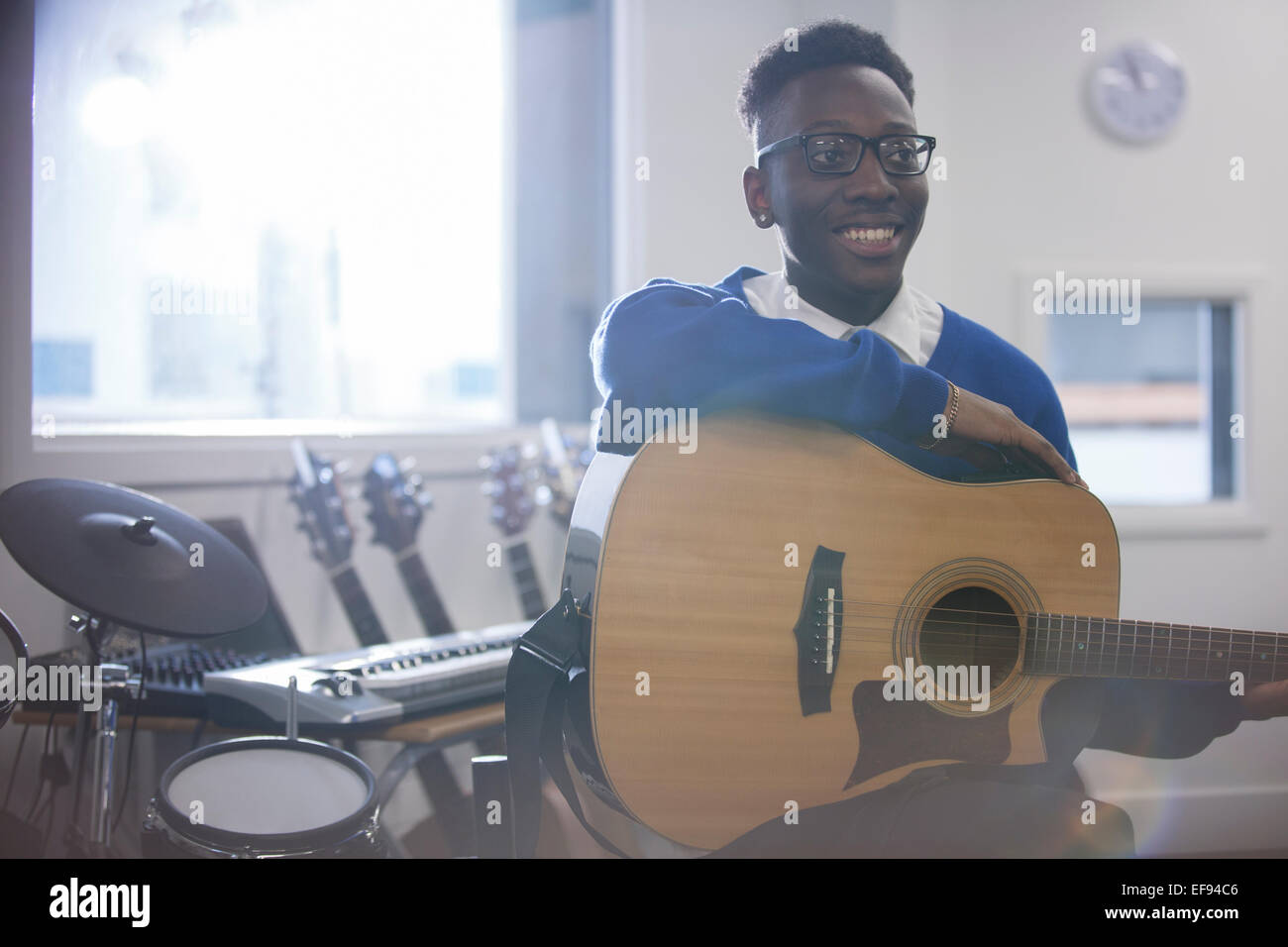 Smiling college student sitting with acoustic guitar in classroom Stock ...