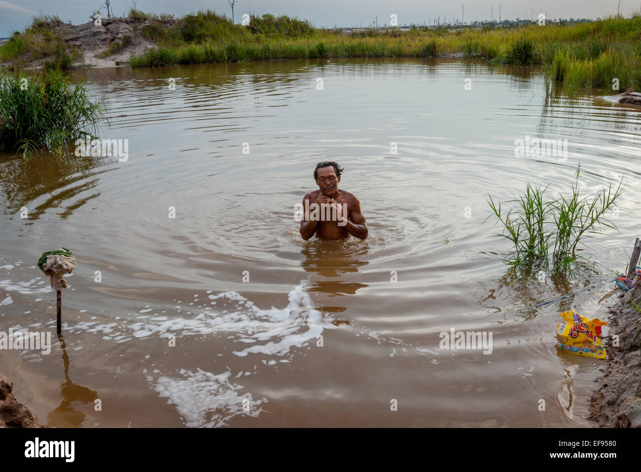 Gold miner bathing on a potentially mercury-polluted pond at Hampalit ...