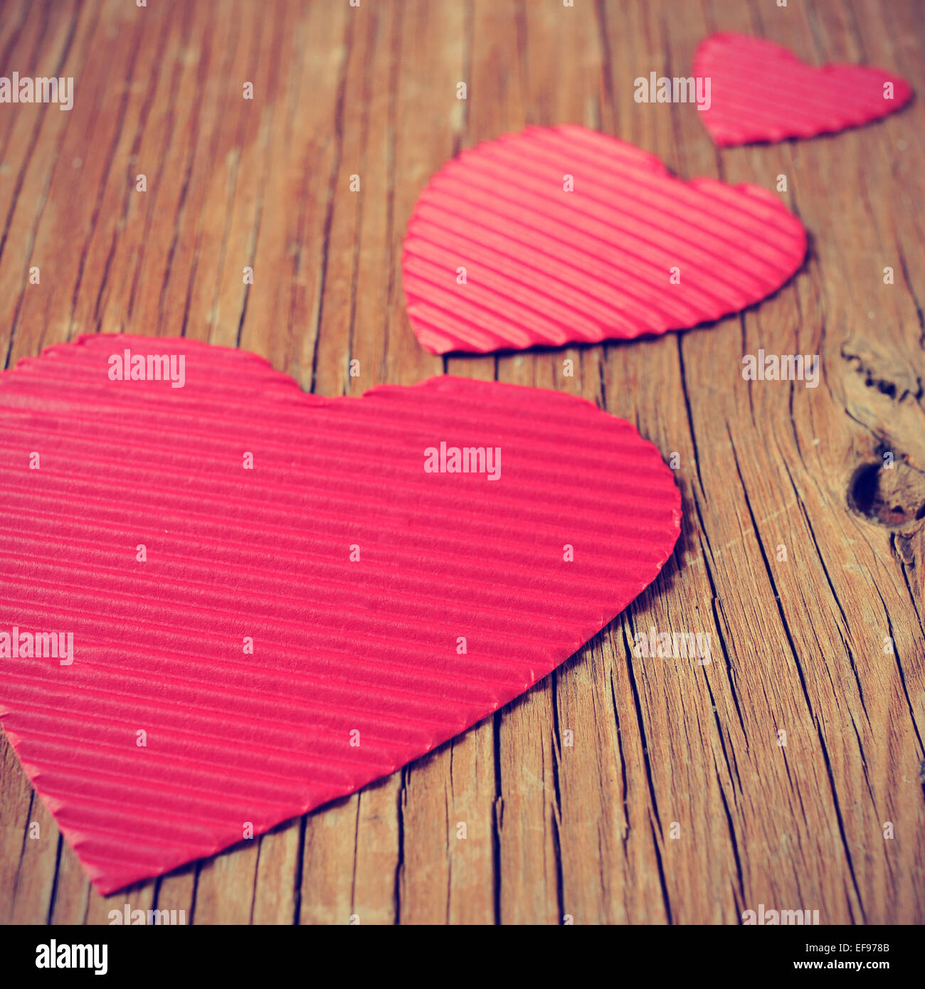 some red hearts of different sizes on a rustic wooden surface, with a ...