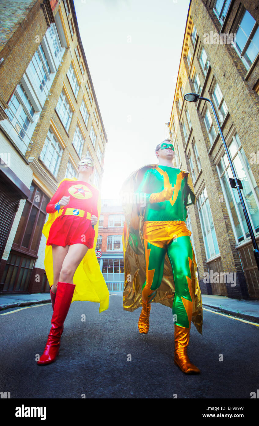 Low angle view of superhero couple running on city street Stock Photo ...