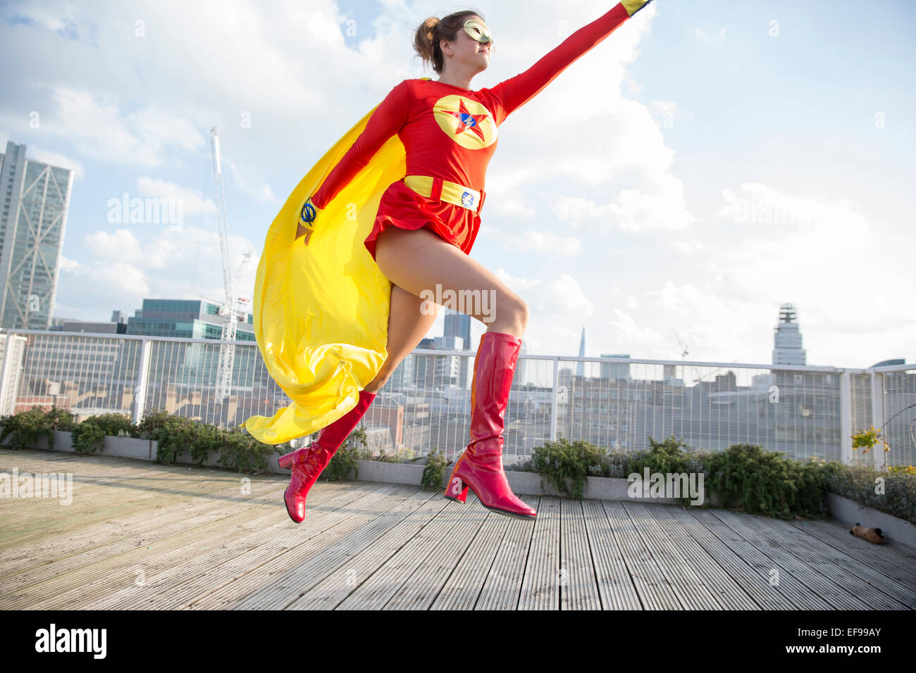 Superhero jumping on city rooftop Stock Photo - Alamy