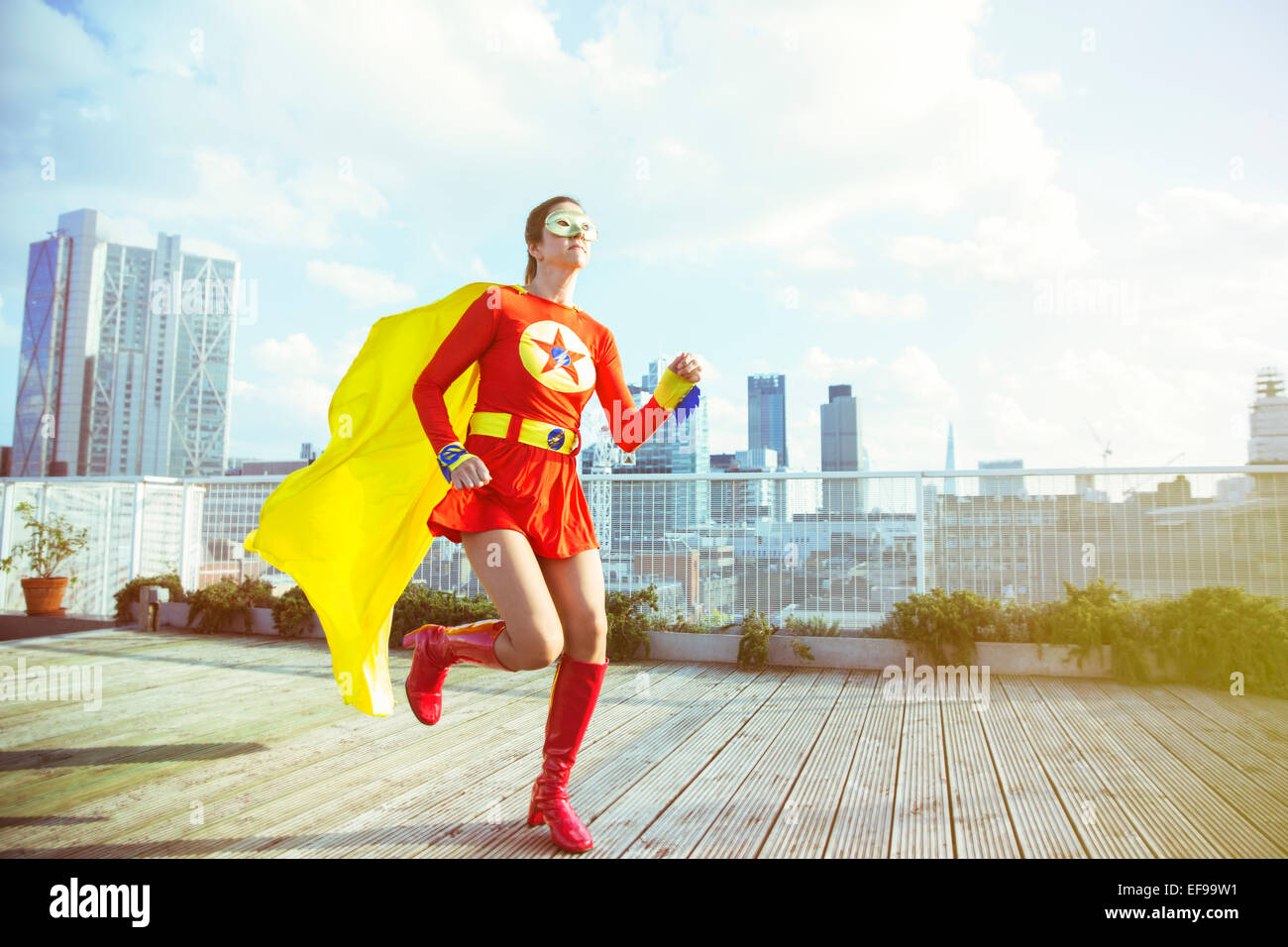 Superhero running on city rooftop Stock Photo - Alamy