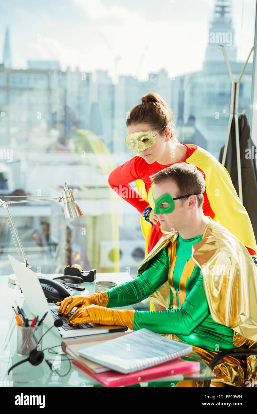 Superheroes working on laptop in office Stock Photo - Alamy