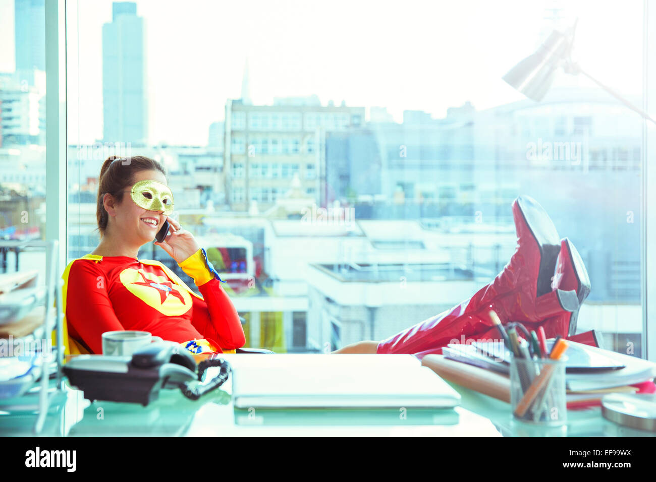 Superhero talking on cell phone at office desk Stock Photo - Alamy