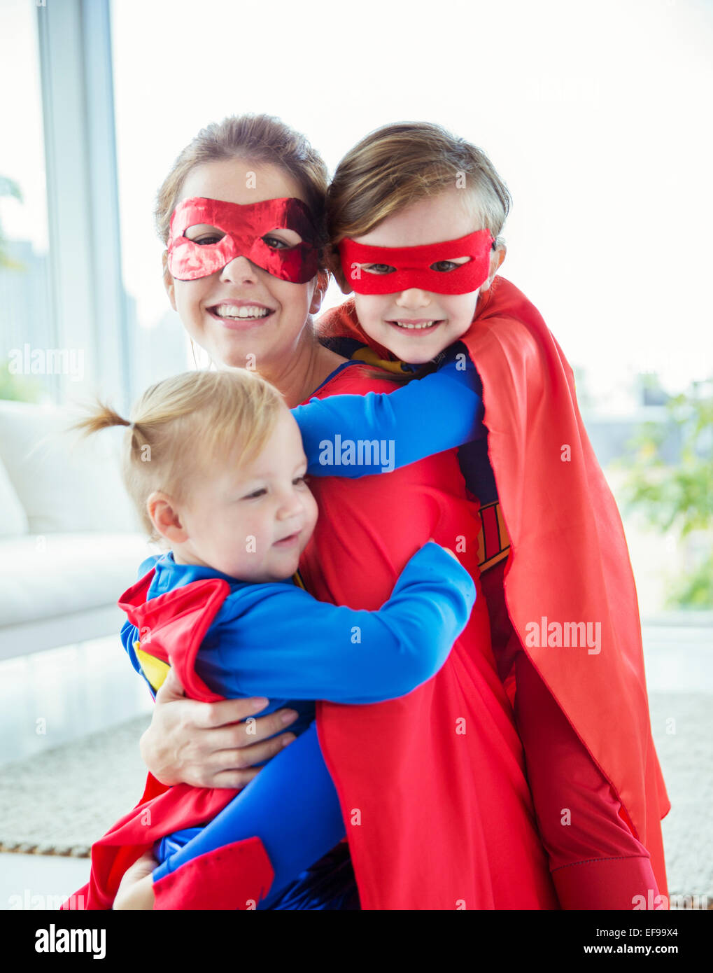 Superhero mother and children hugging in living room Stock Photo - Alamy