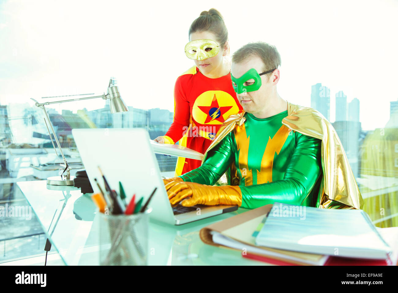 Superheroes working with laptop in office Stock Photo - Alamy
