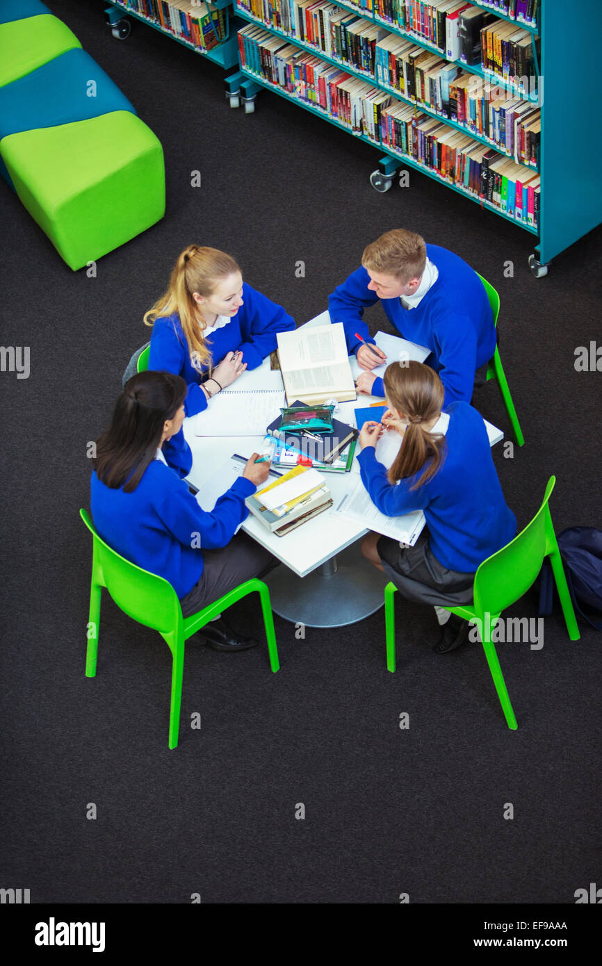 Elevated view of four students sitting and learning together in library ...