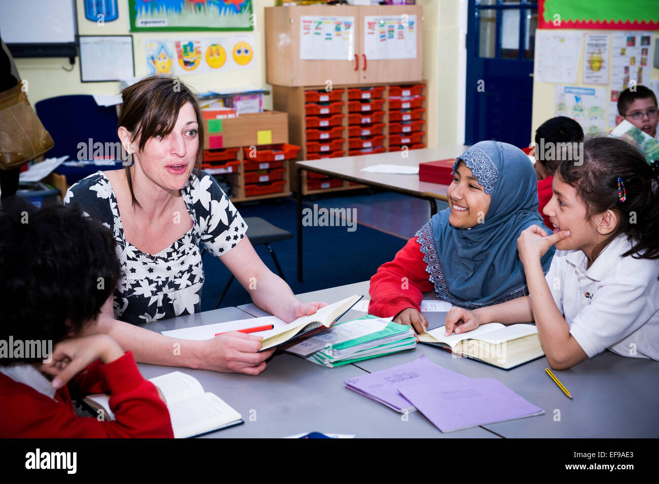 Smiling teacher with happy students in primary school classroom UK ...