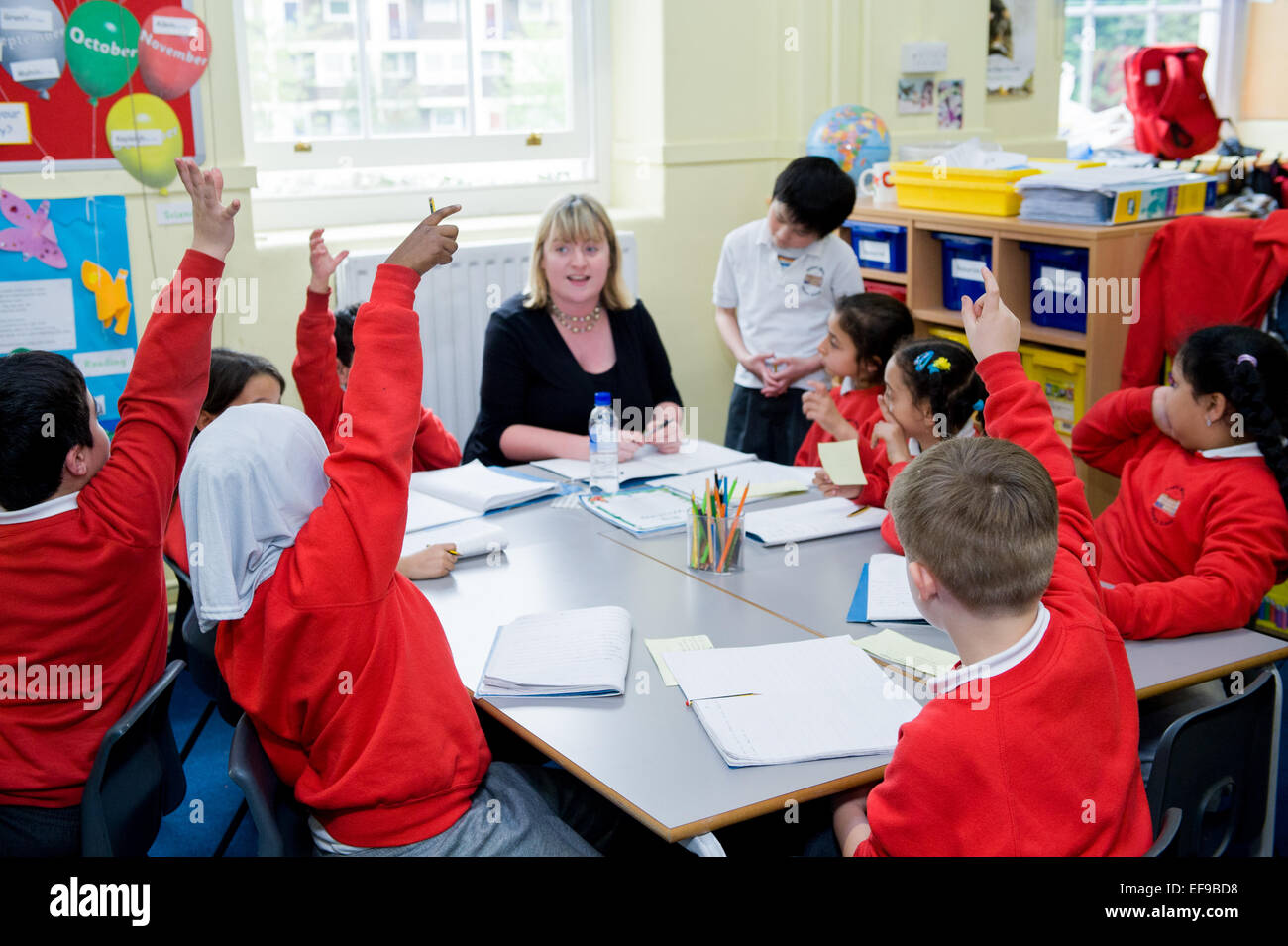 Teacher asking question in class at London Primary school. Engaged ...