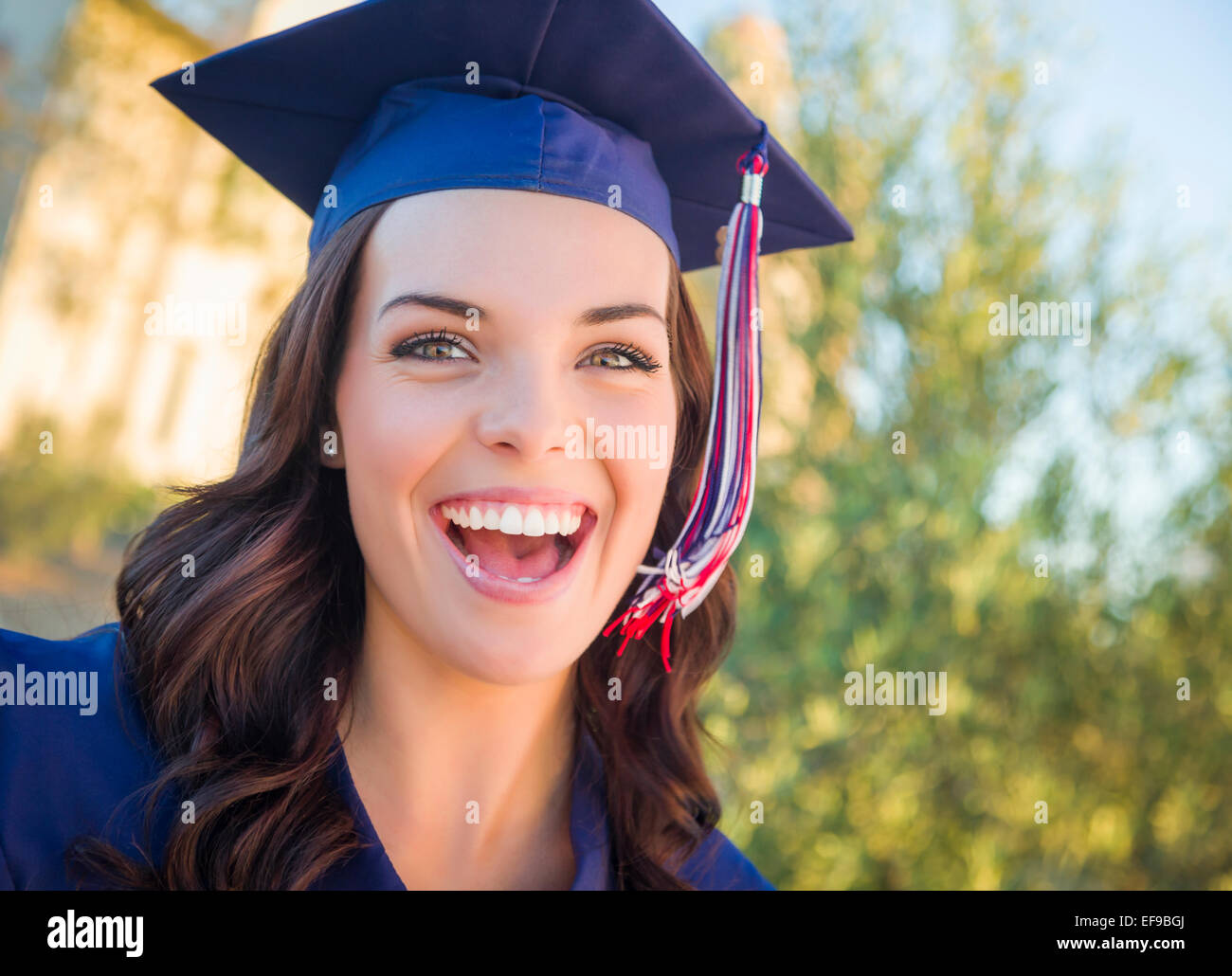 Happy Graduating Mixed Race Woman In Cap and Gown Celebrating on Campus ...