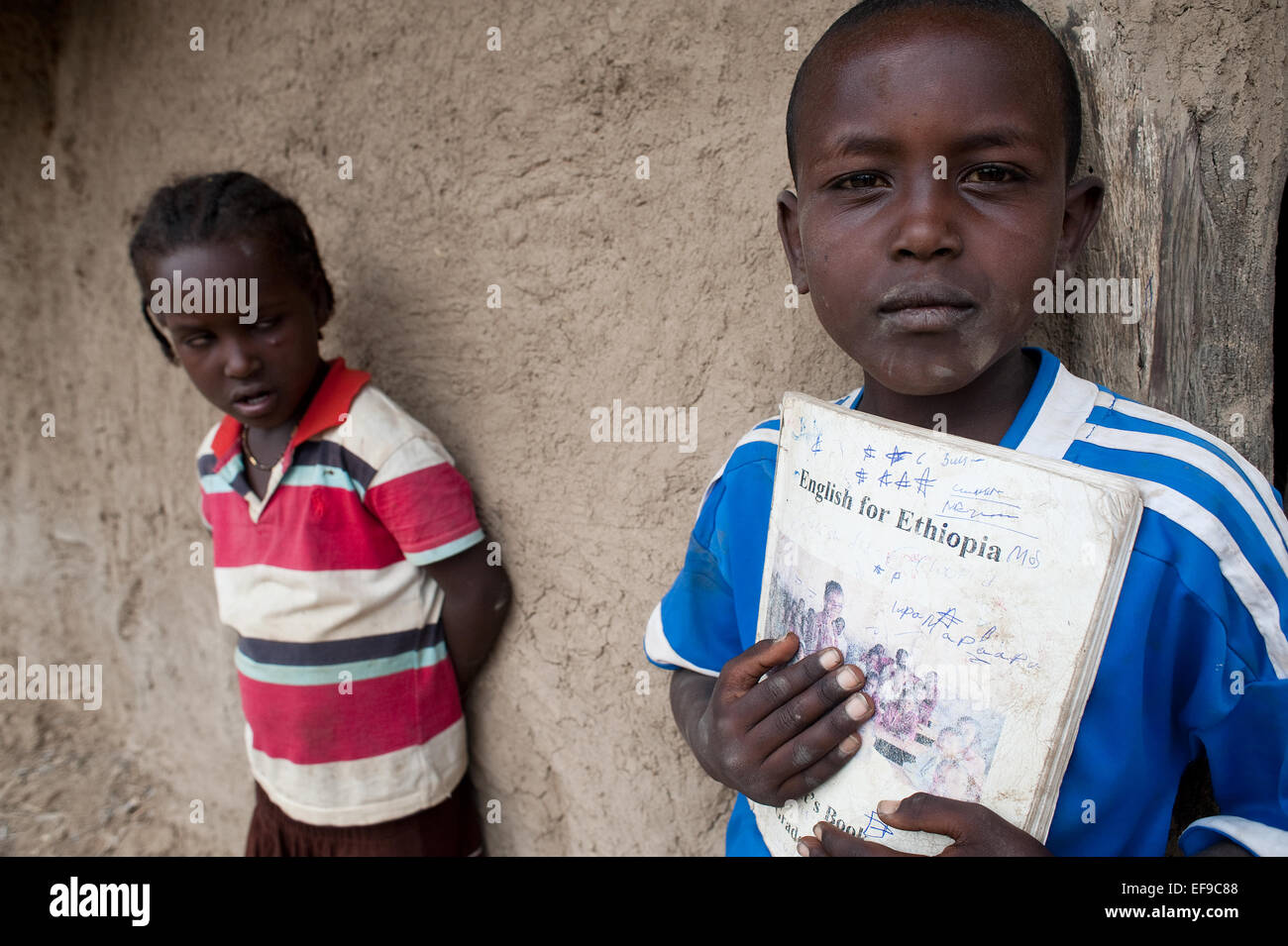 Schoolboy holding his english book while a schoolgirl is looking him ...
