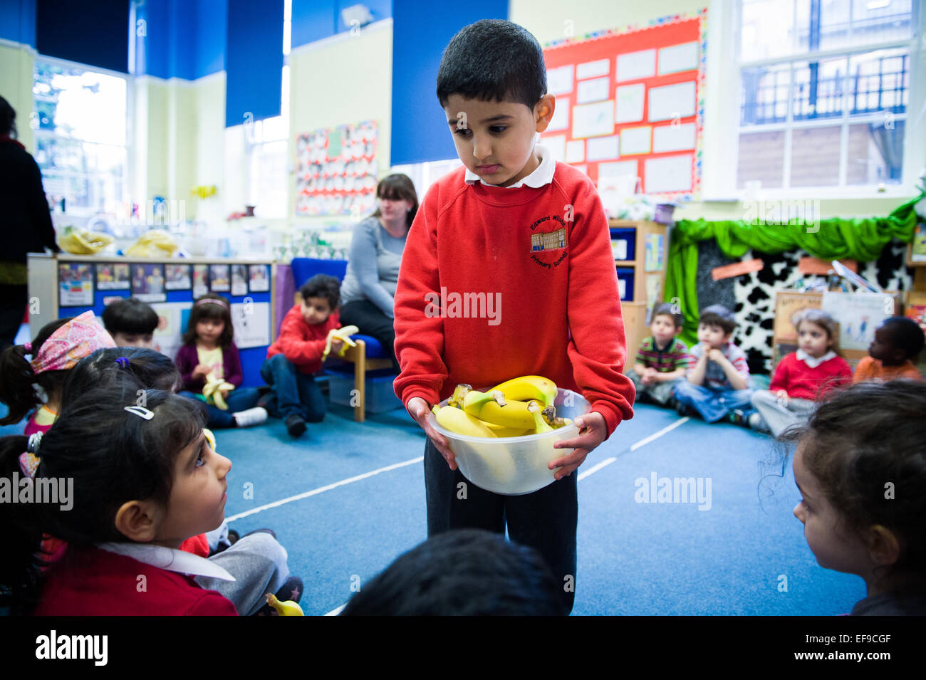 Boy giving out bananas to fellow students as part of a healthy eating ...