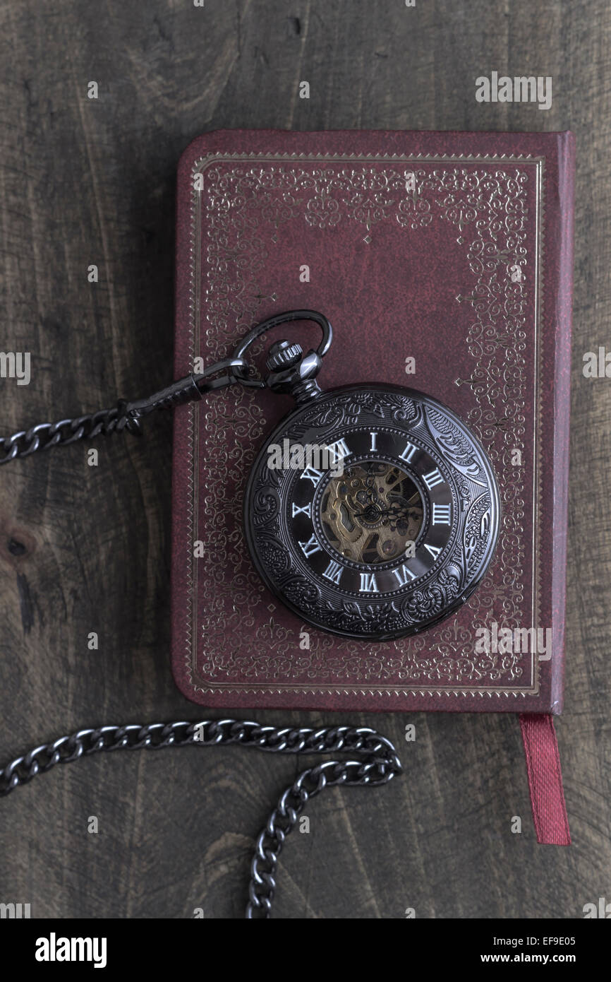 pocket watch on old book over rustic wooden background Stock Photo - Alamy