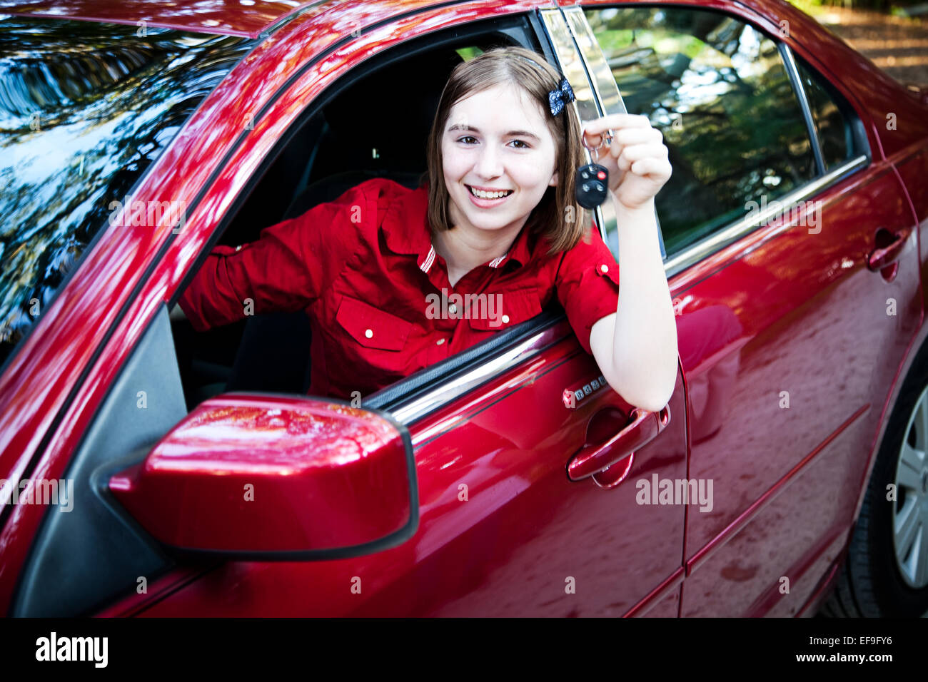Teenage girl with her driver's license driving a new car and holding ...