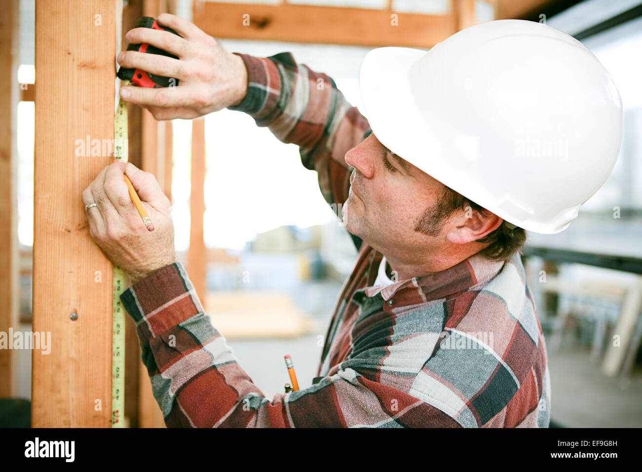 Carpenter taking measurements on a construction site Stock Photo - Alamy