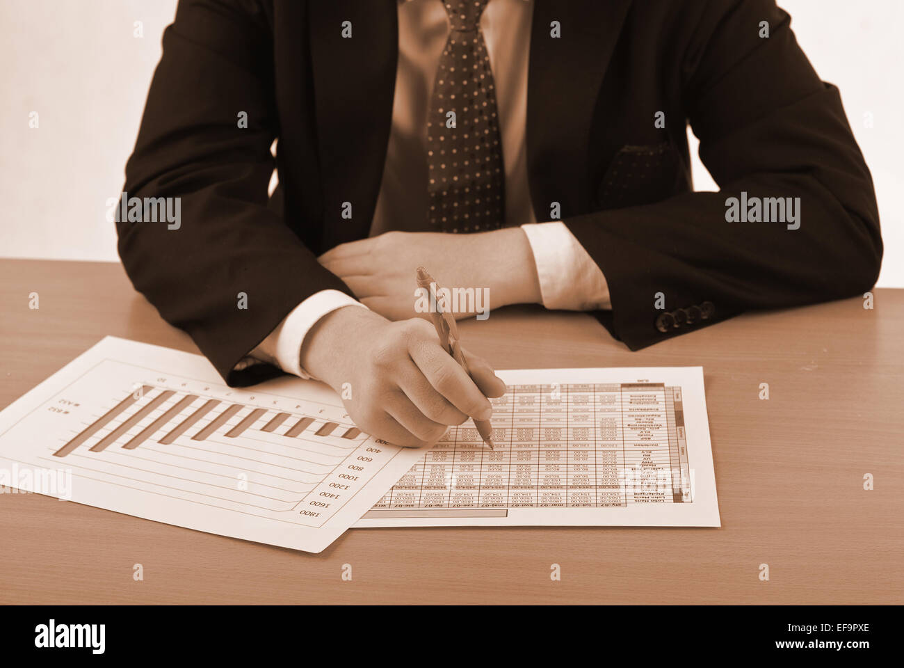 Businessman examining graphs at desk in his office - vintage effect ...