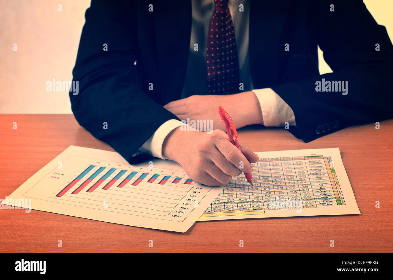 Businessman examining graphs at desk in his office - vintage effect ...