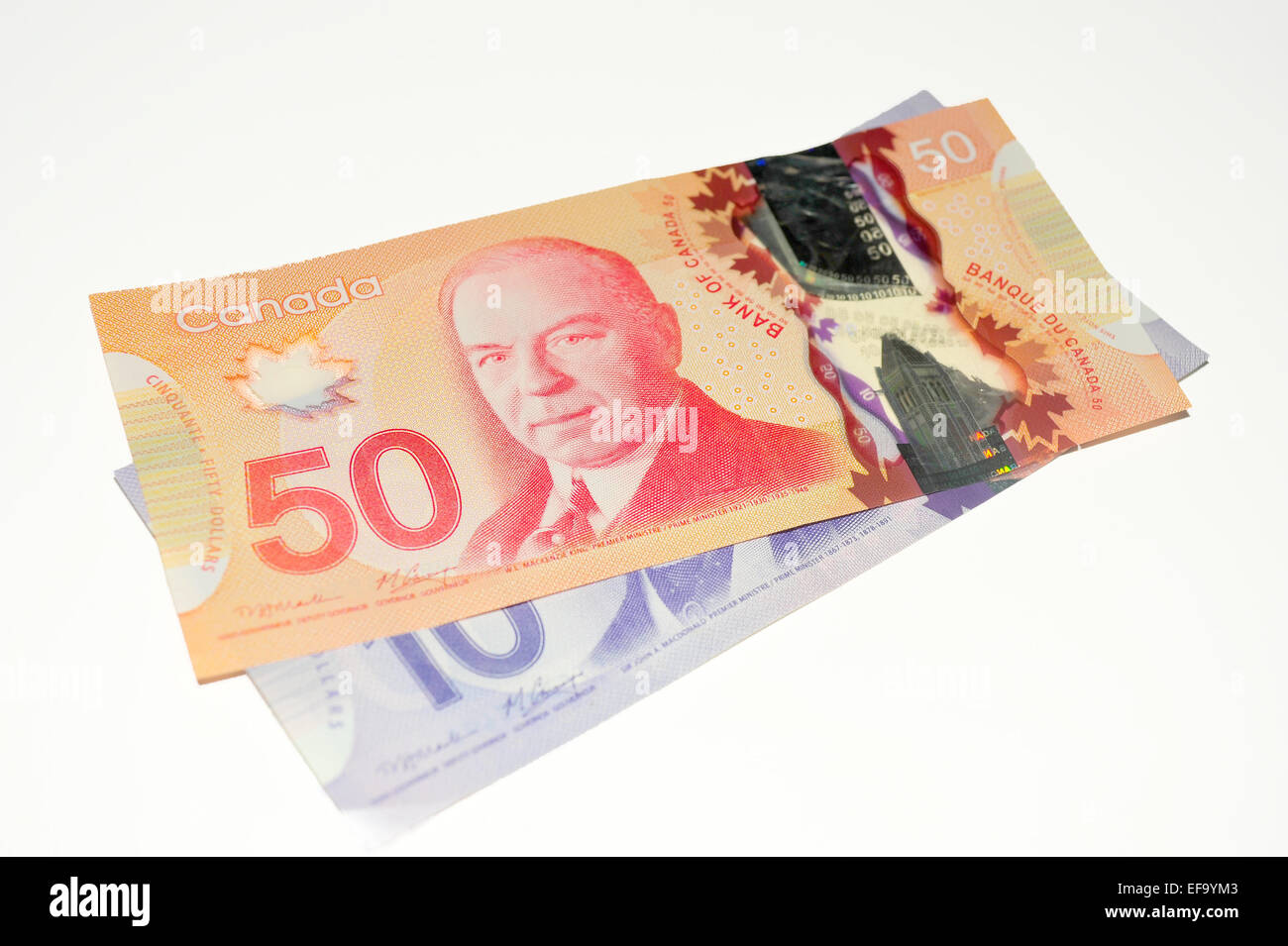Canadian $50 and $10 currency notes photographed against a white ...