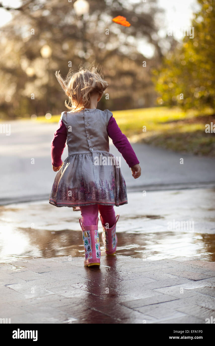 A little girl walk through puddles on a street Stock Photo - Alamy
