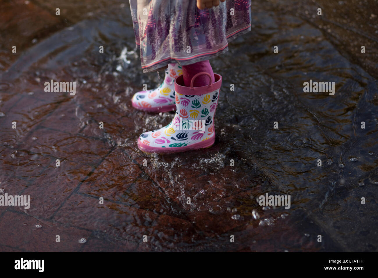 A girl jumping in rain puddles Stock Photo - Alamy