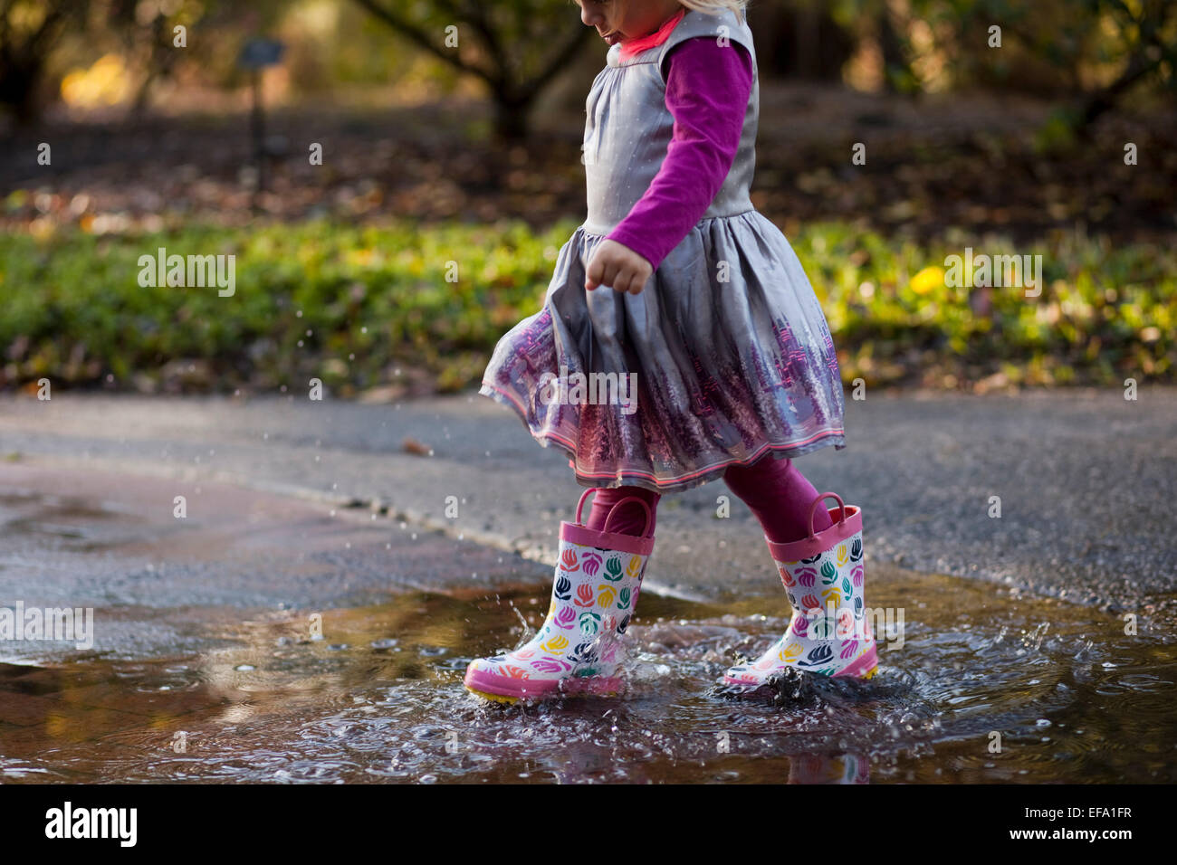 A girl jumping in rain puddles Stock Photo - Alamy