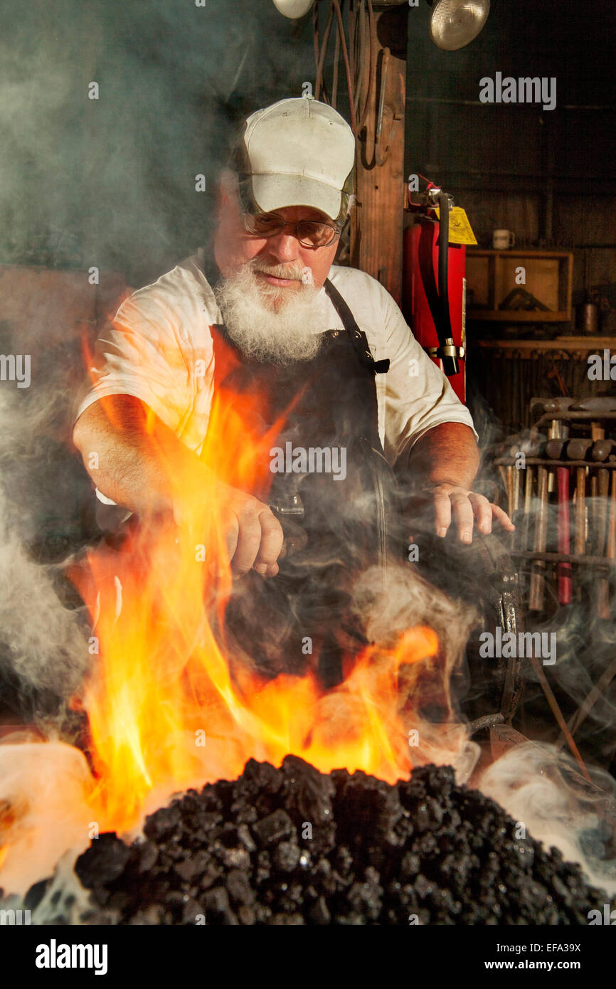 A modern day amateur blacksmith stokes his traditional coal forge as ...
