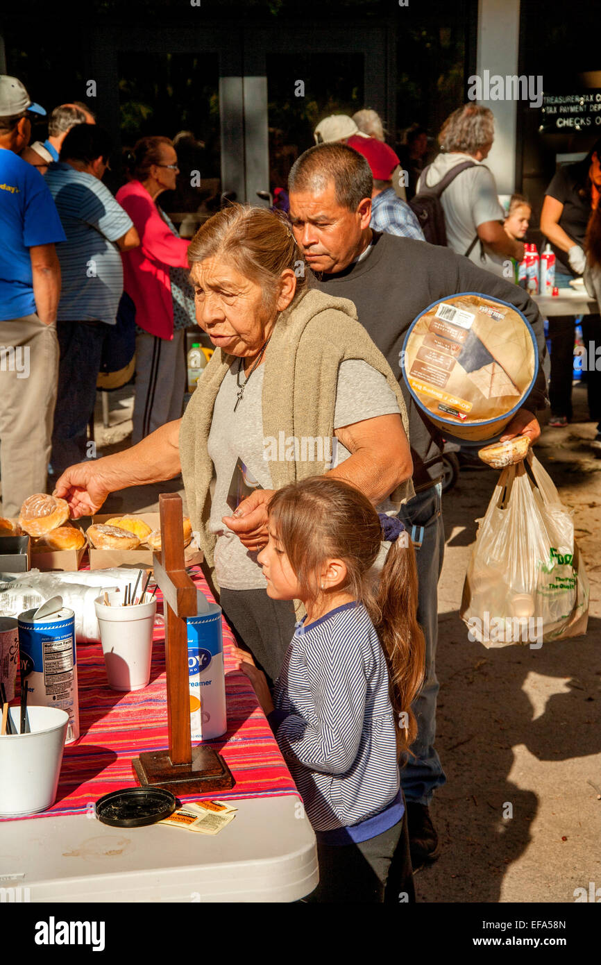 Three generations of a Hispanic family collect food from a church ...