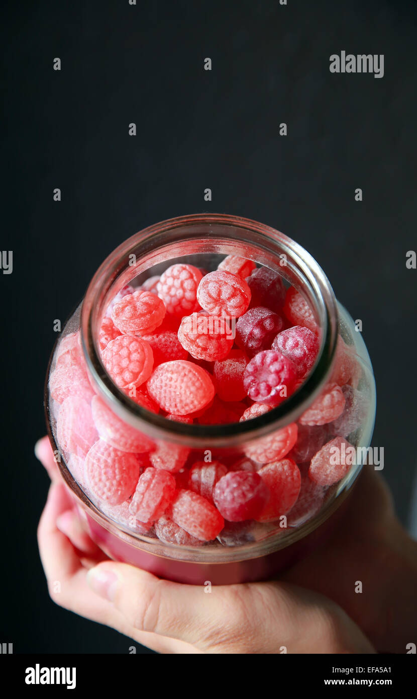 Red candy in a glass candy jar with black background Stock Photo - Alamy