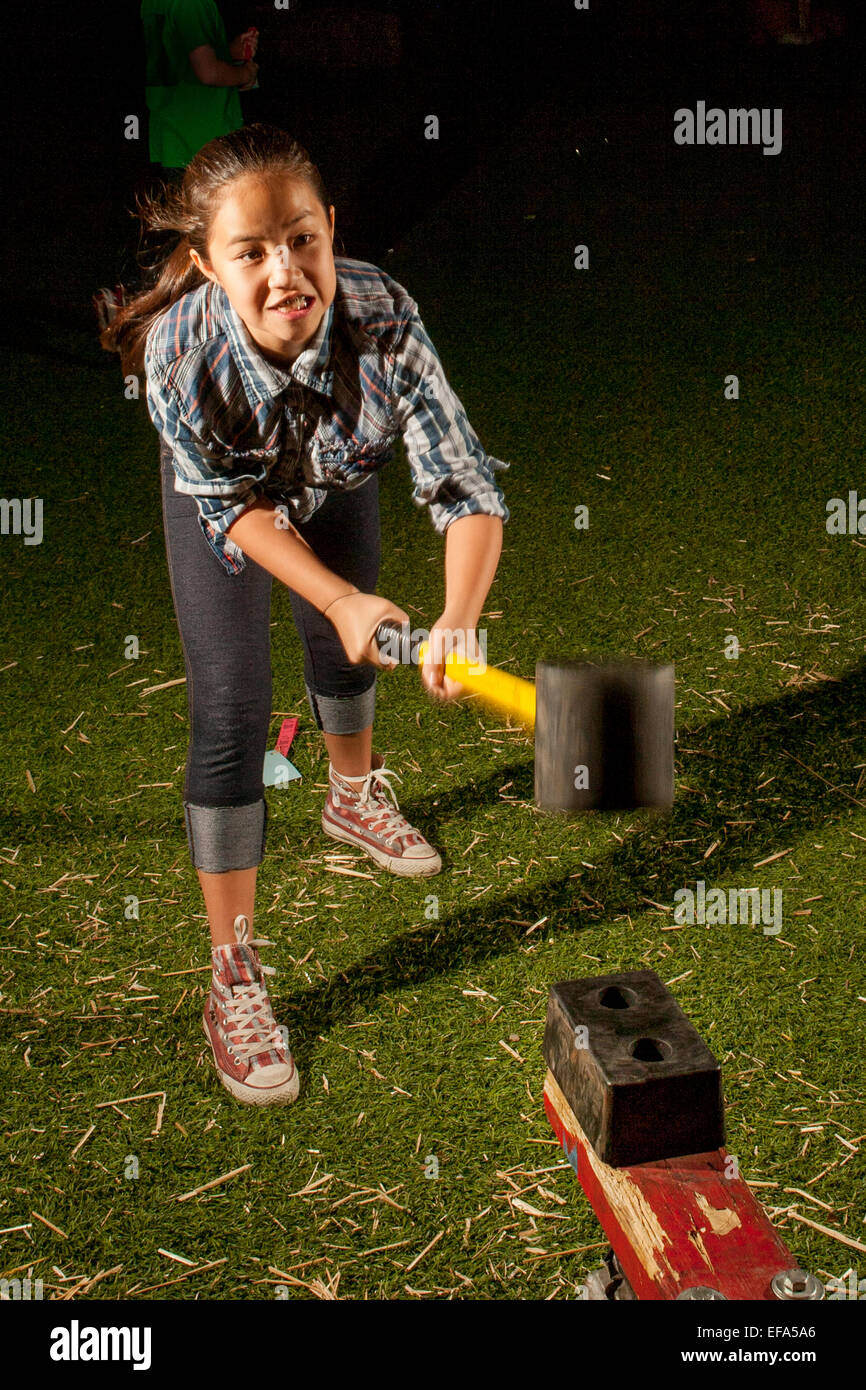 A teen girl swings a mallet at a strength machine during an evening ...