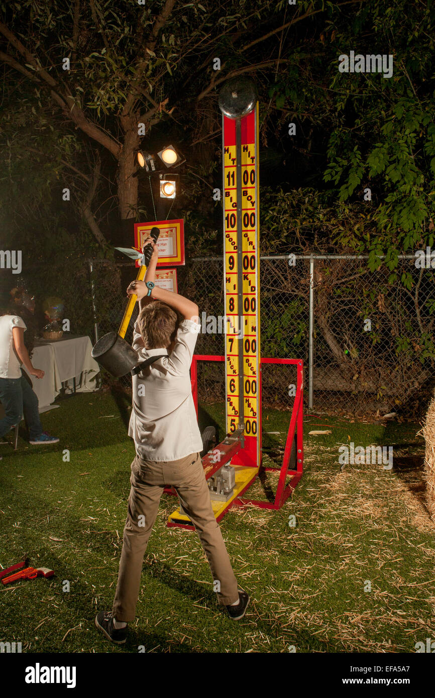 A teen boy swings a mallet at a strength machine during an evening ...