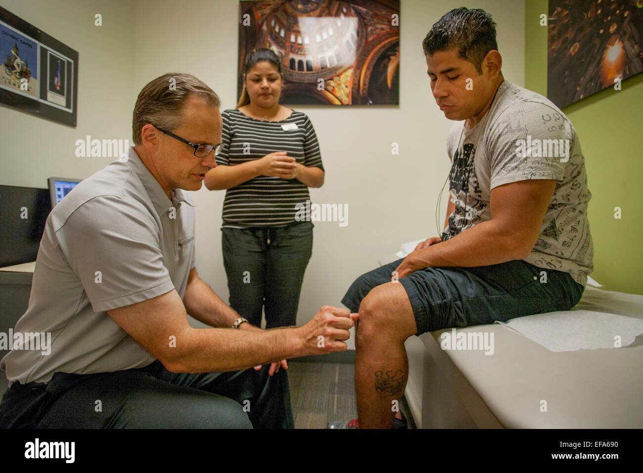 An orthopedic doctor examines a male Hispanic patient with a knee ...
