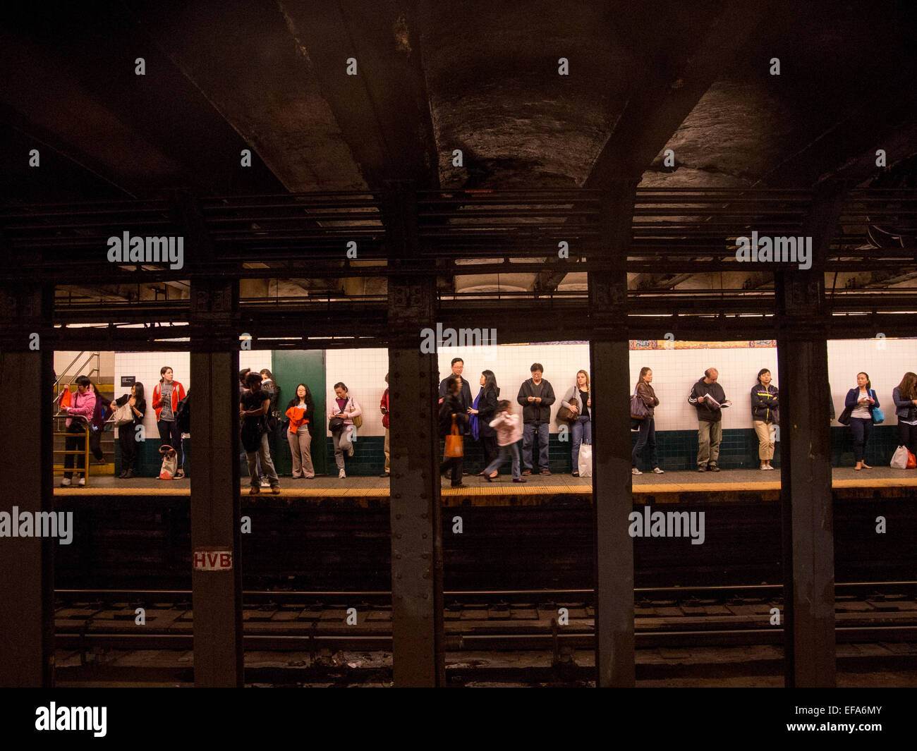 Multiracial travelers wait for the train on a subway station platform ...