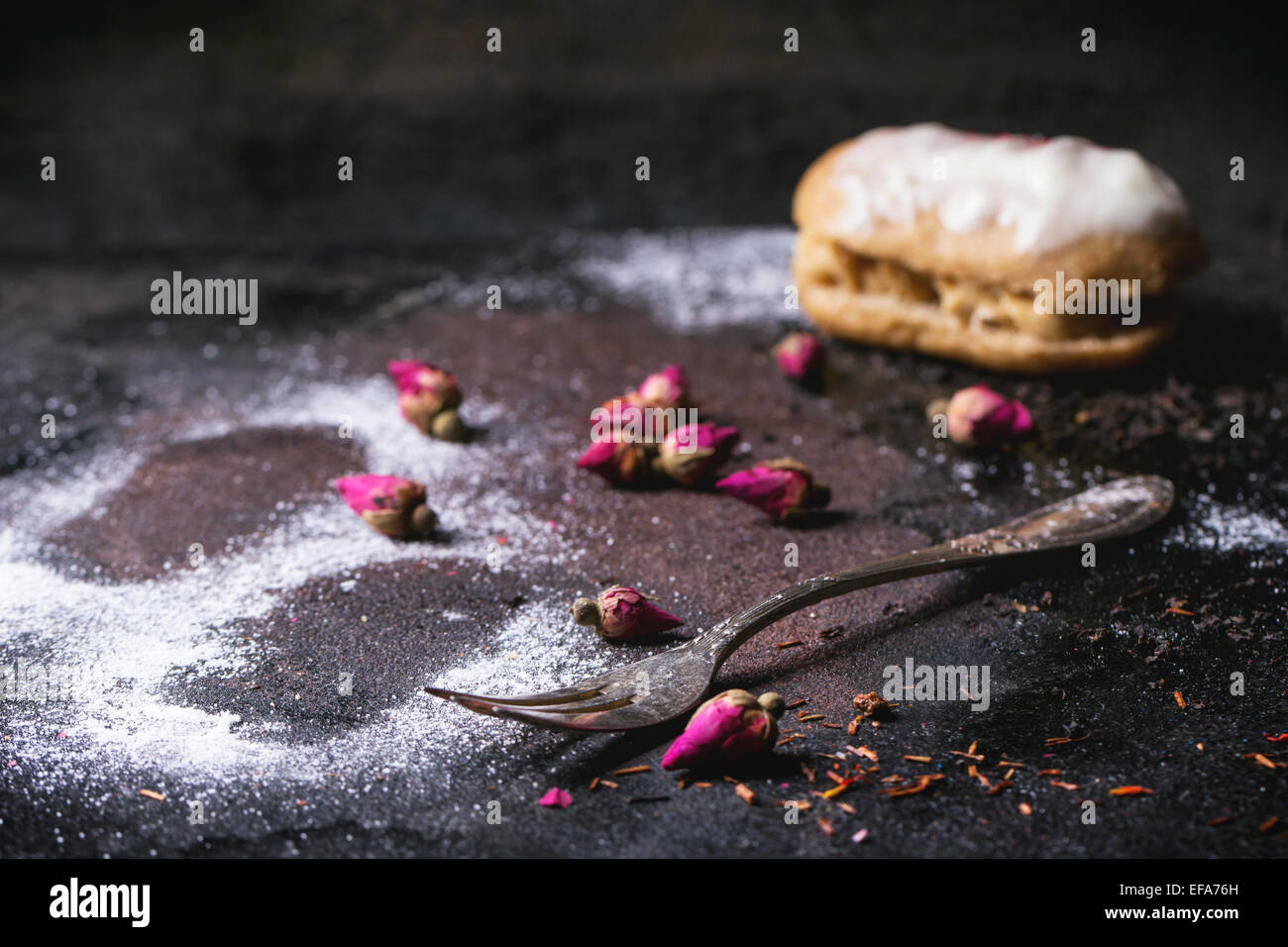 Eclairs and trace of the eclair in sugar powder, with dry tea rose buds ...