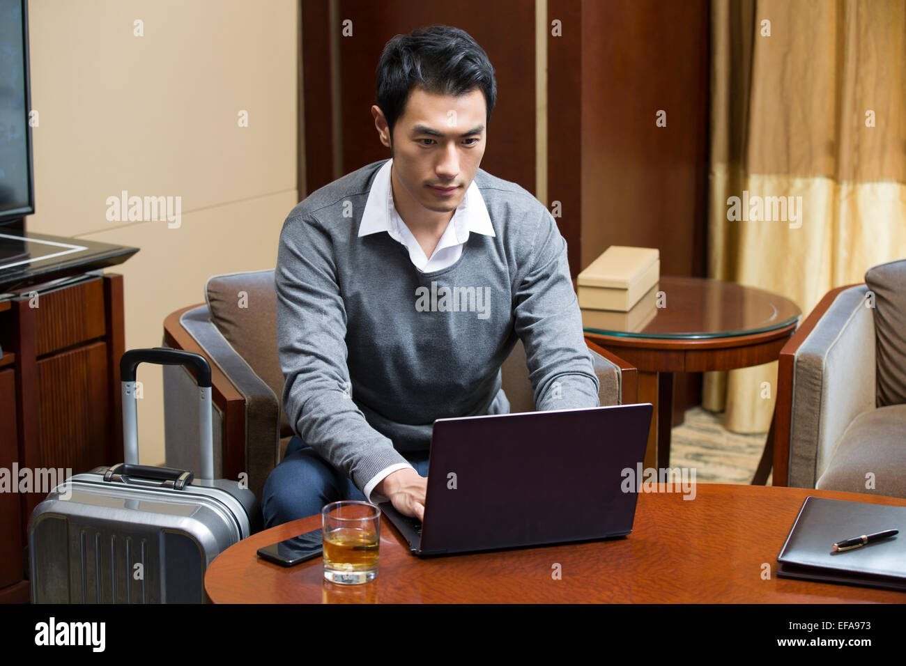Young businessman using laptop in hotel room Stock Photo - Alamy