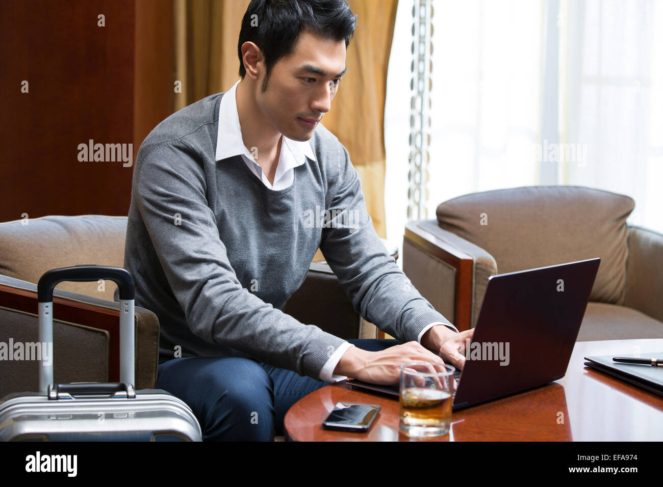Young businessman using laptop in hotel room Stock Photo - Alamy