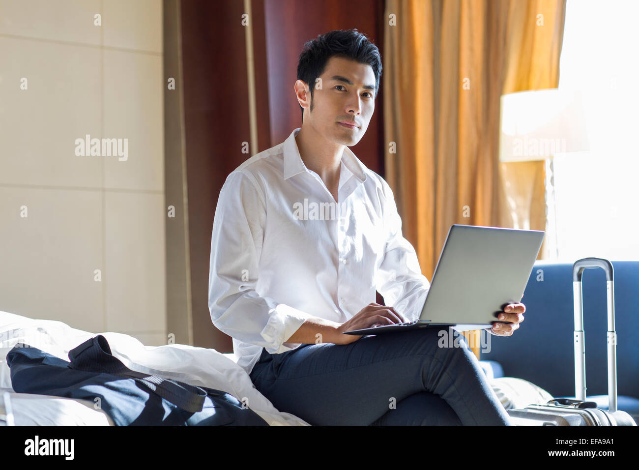 Young businessman using laptop in hotel room Stock Photo - Alamy