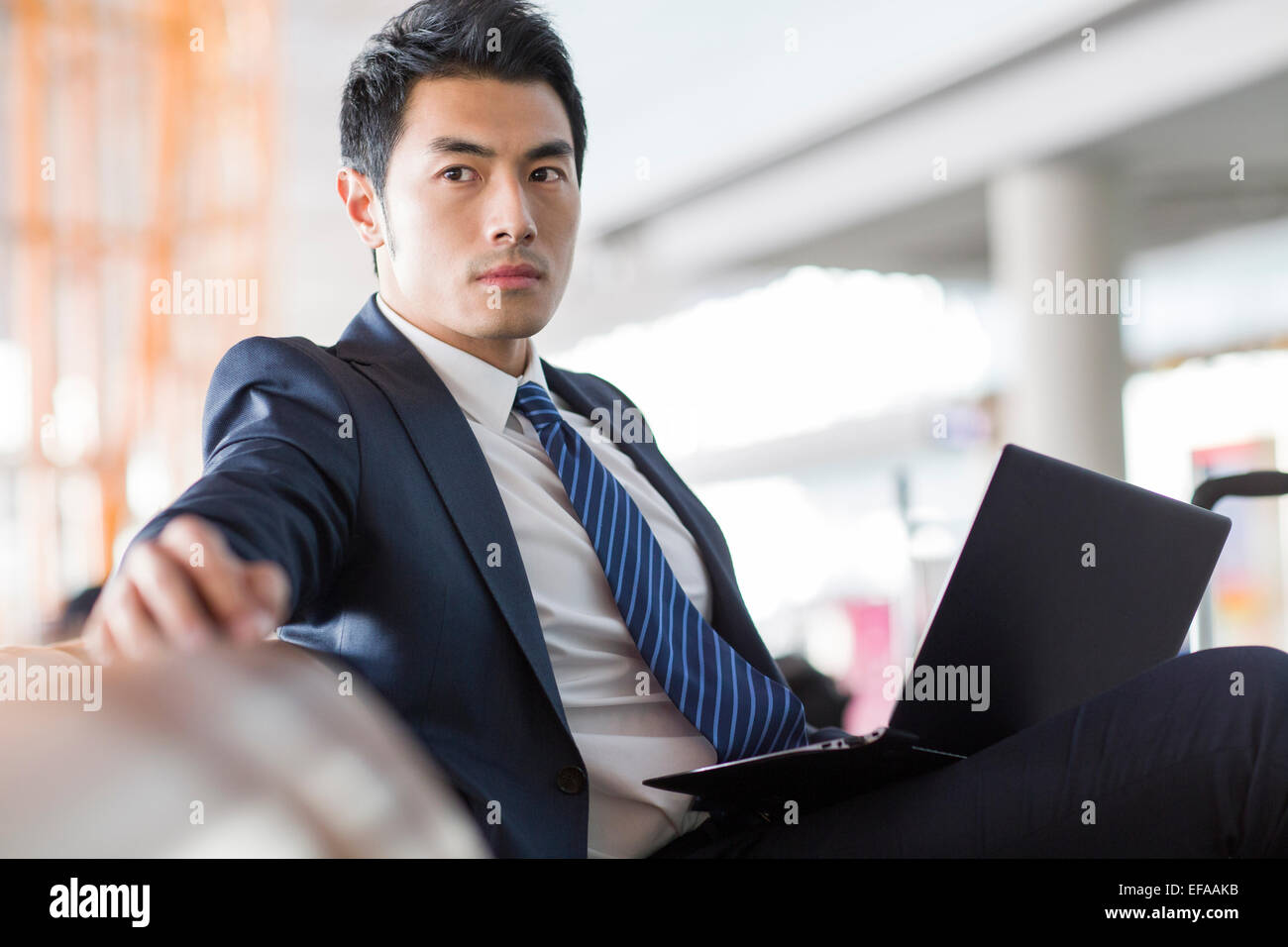 Young businessman using laptop in airport Stock Photo - Alamy