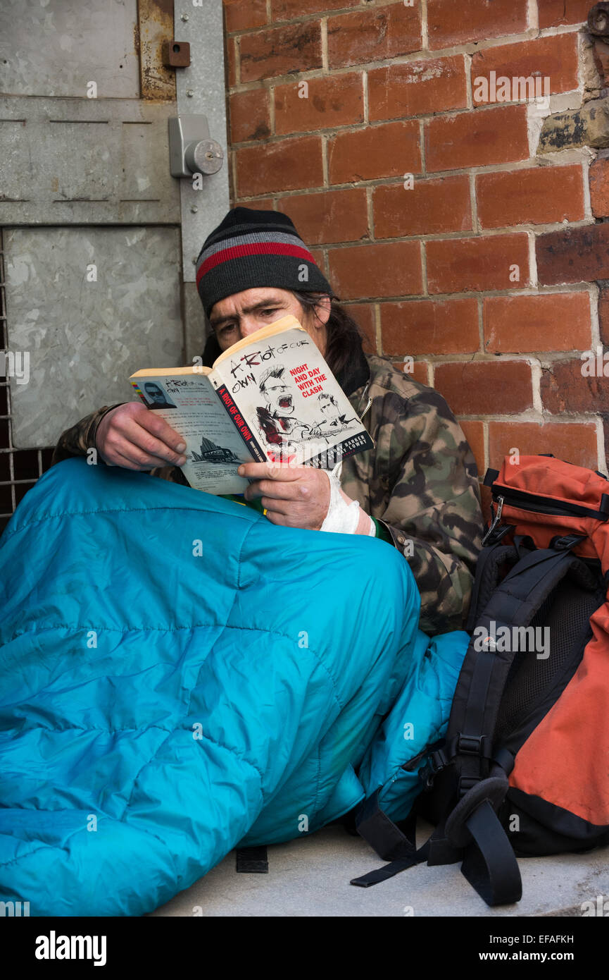 A homeless man reading a book while in his sleeping bag Stock Photo - Alamy