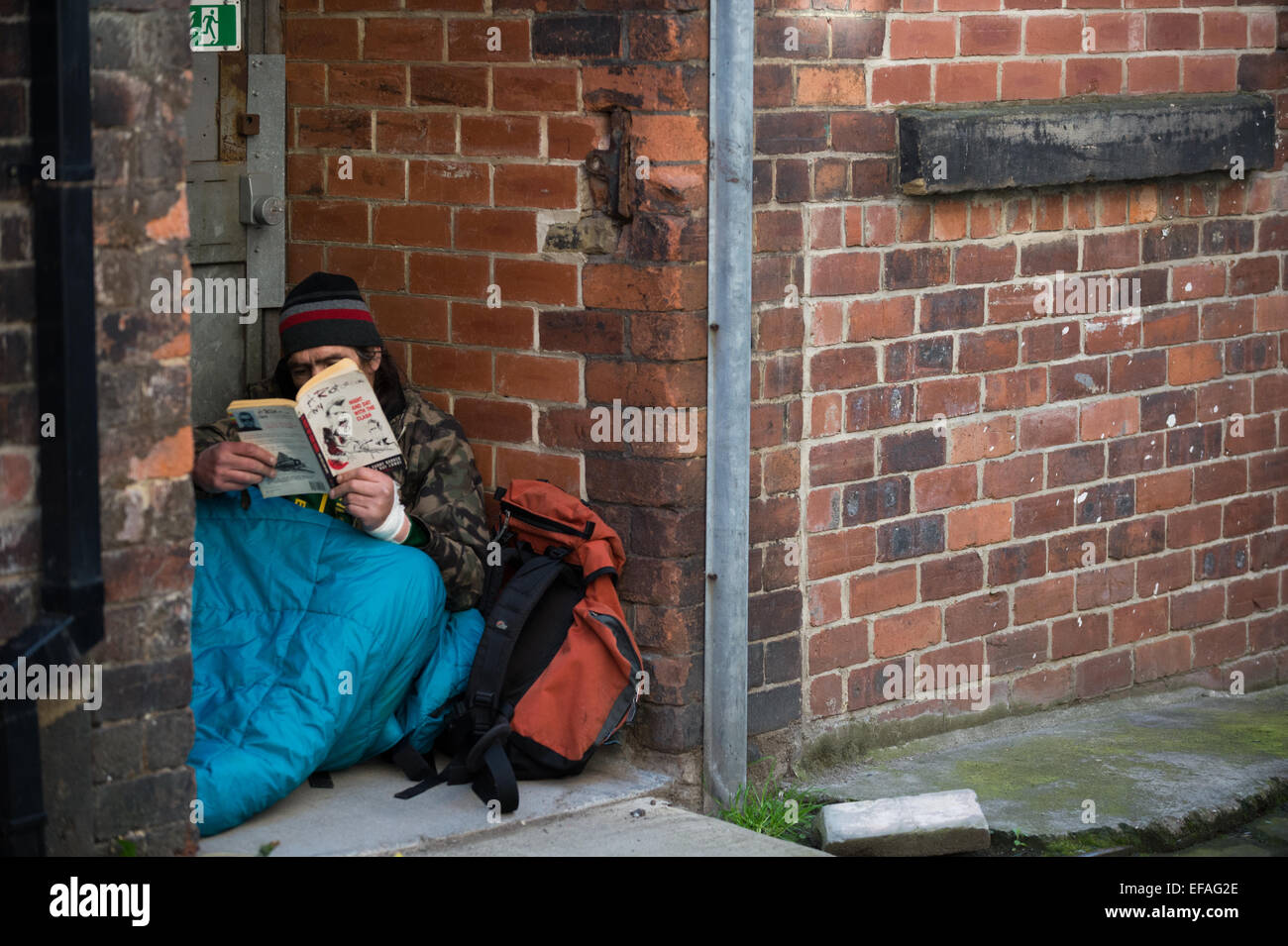 A homeless man reading a book while in his sleeping bag Stock Photo - Alamy