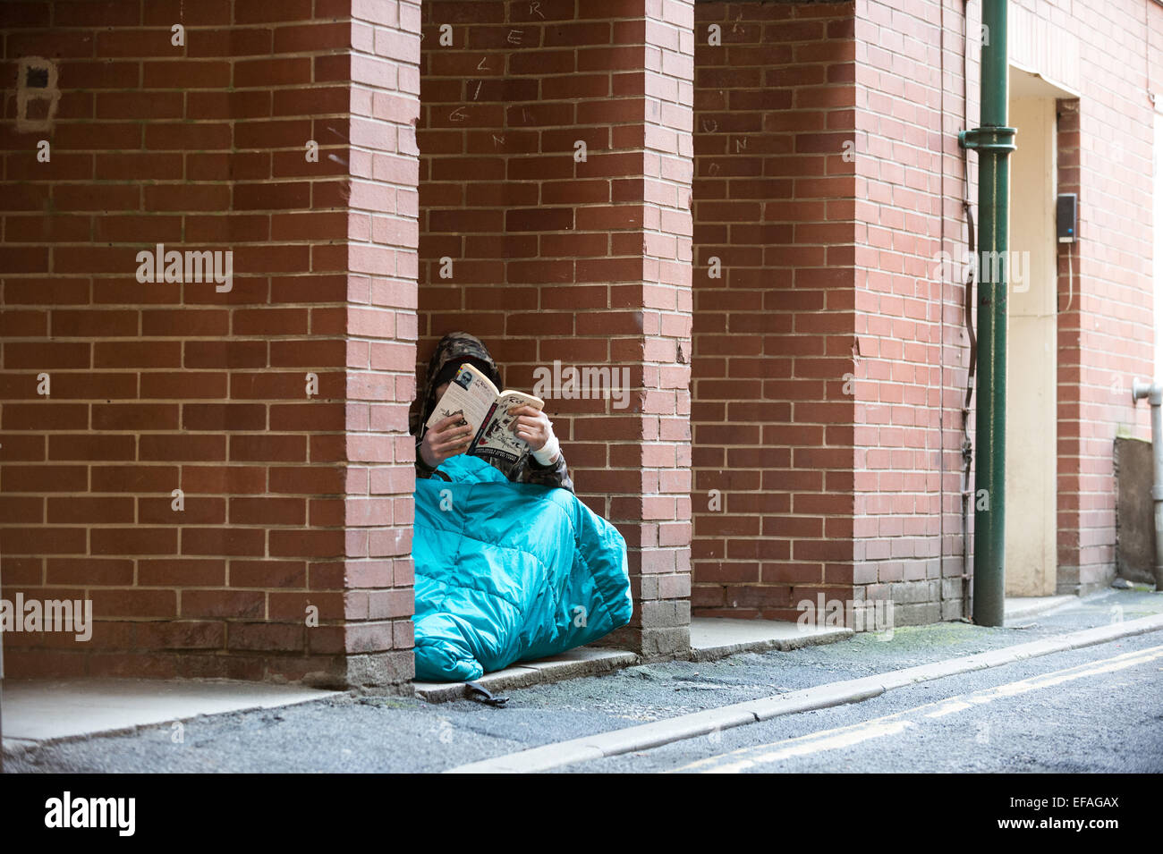 A homeless man reading a book while in his sleeping bag Stock Photo - Alamy