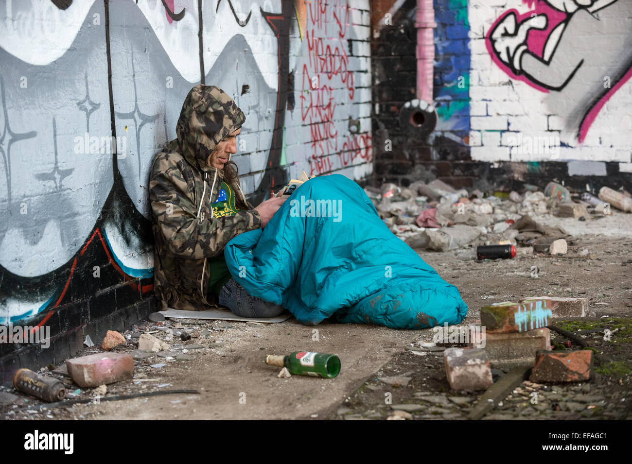 A homeless man reading a book while in his sleeping bag Stock Photo - Alamy