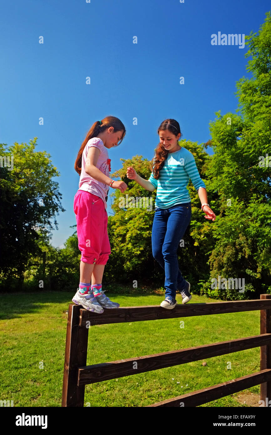 Two young sisters tight rope walking on a fence in North County Dublin ...