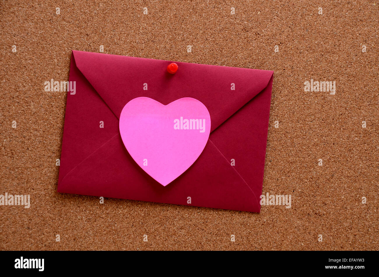 Heart shaped paper notes with envelope pinned into brown corkboard ...