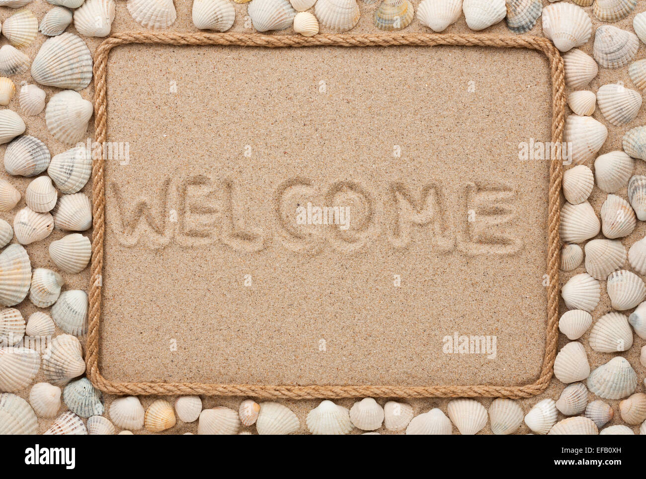 Beautiful frame of rope and sea shells on the sand with text welcome ...